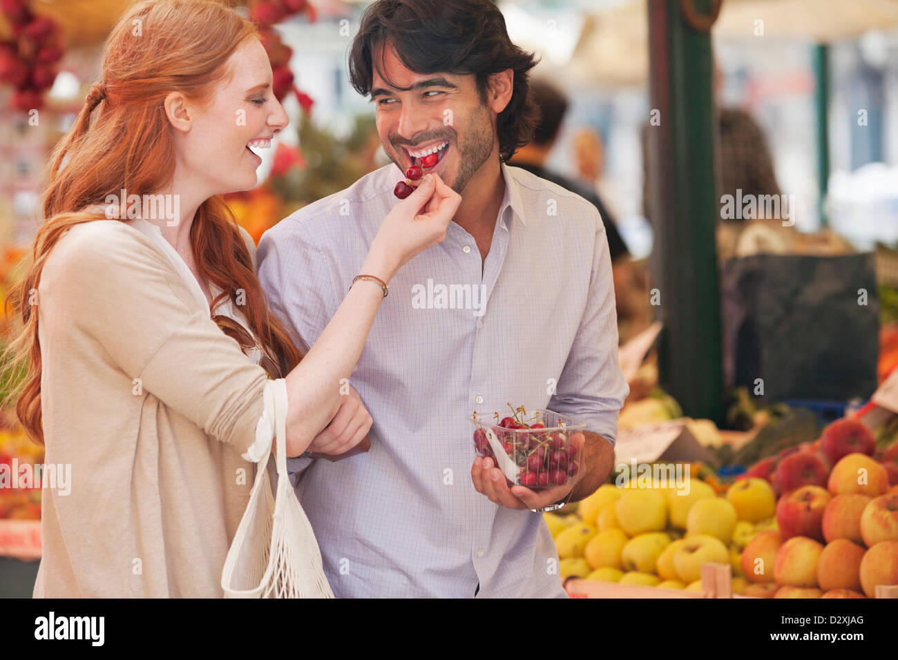 Smiling couple tasting fruit in market Stock Photo - Alamy