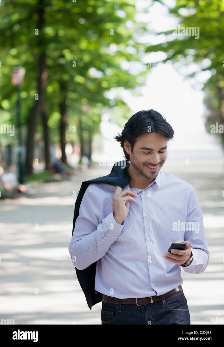 Businessman checking cell phone in park Stock Photo - Alamy