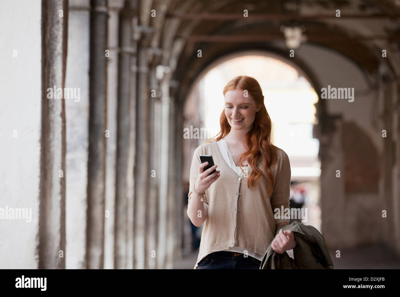 Smiling woman checking cell phone in corridor Stock Photo - Alamy