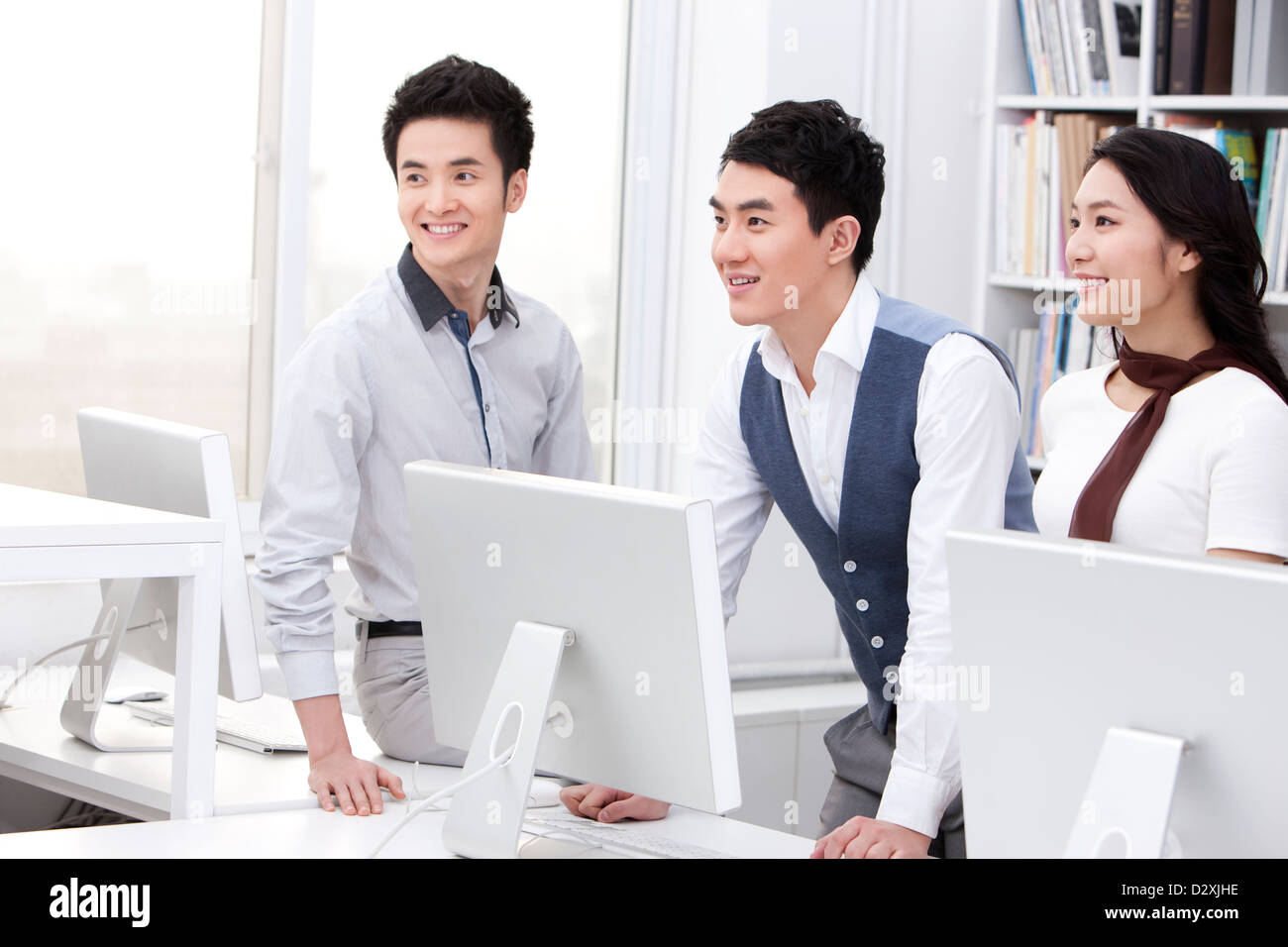 Cheerful office workers using computers in studio Stock Photo - Alamy