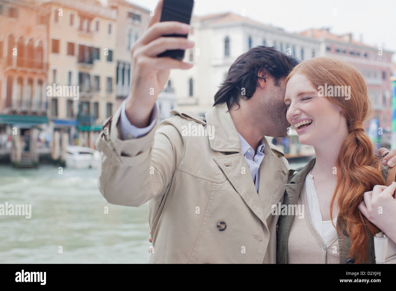 Laughing couple taking self-portrait with camera phone at waterfront in ...