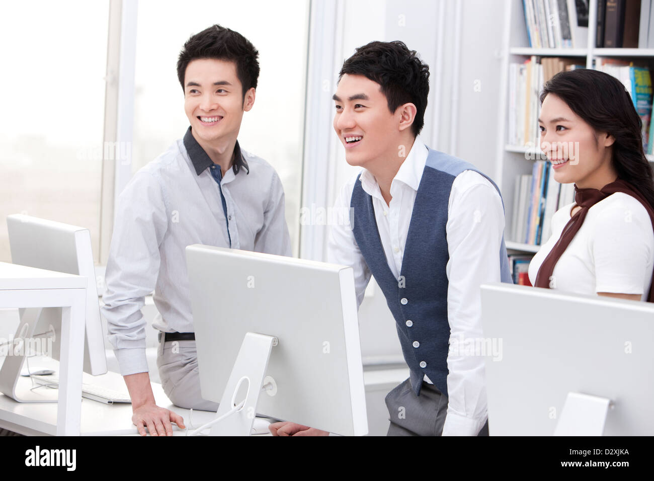 Cheerful office workers using computers in studio Stock Photo - Alamy