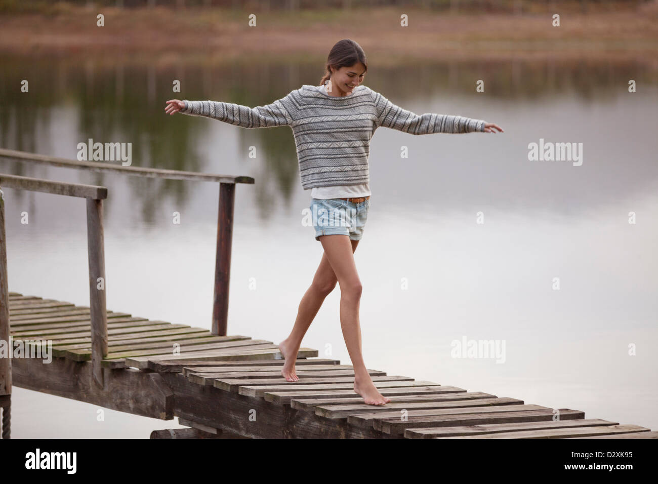 Woman walking on dock over lake with arms outstretched Stock Photo - Alamy