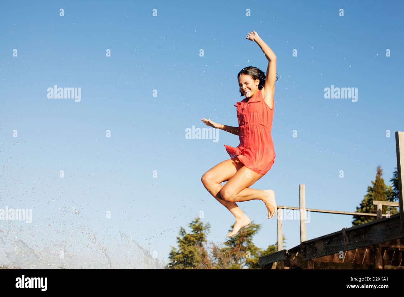 Smiling woman jumping off dock Stock Photo - Alamy