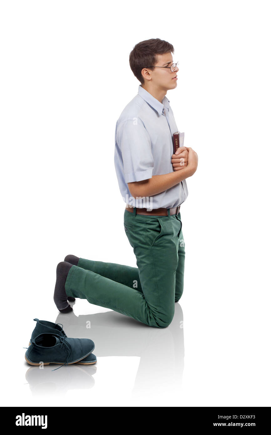 Young man humble knelt for prayer with the Bible in hands and a pair of ...