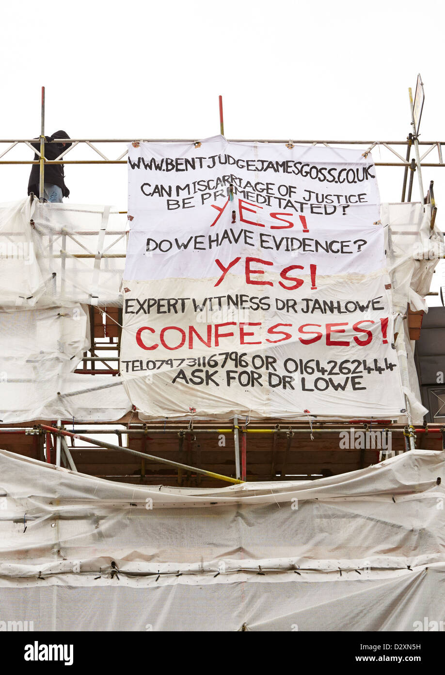 A man protesting about a perceived injustice displays a banner from a ...