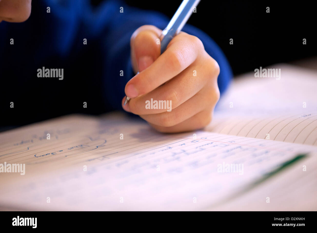 primary school boy writing in exercise book Stock Photo - Alamy