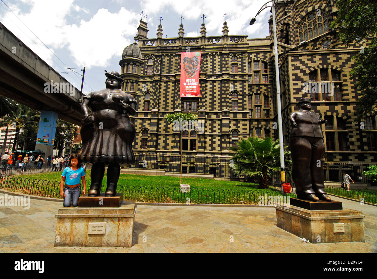 Colombia, Medellin, girl by a statue in the center and buildings in the ...