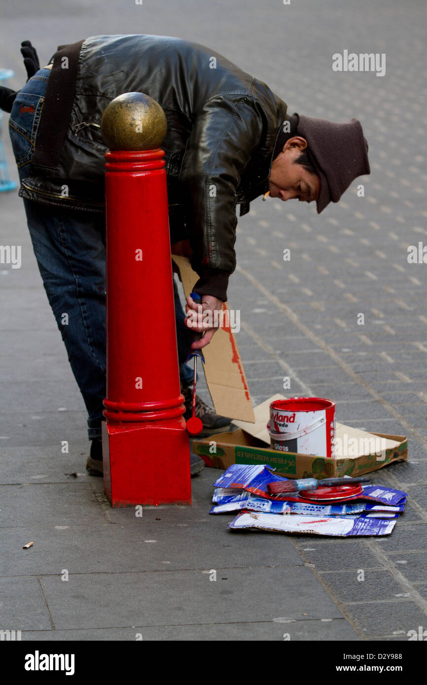 London, UK. 4th February 2013. A man paints a bollard with red paint in ...