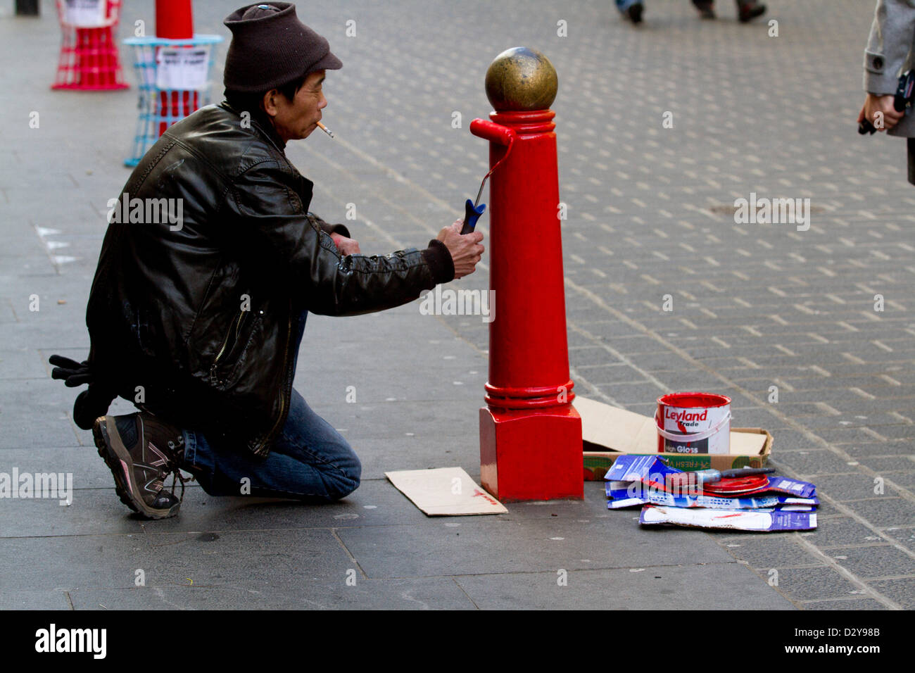 London, UK. 4th February 2013. A man paints a bollard with red paint in ...