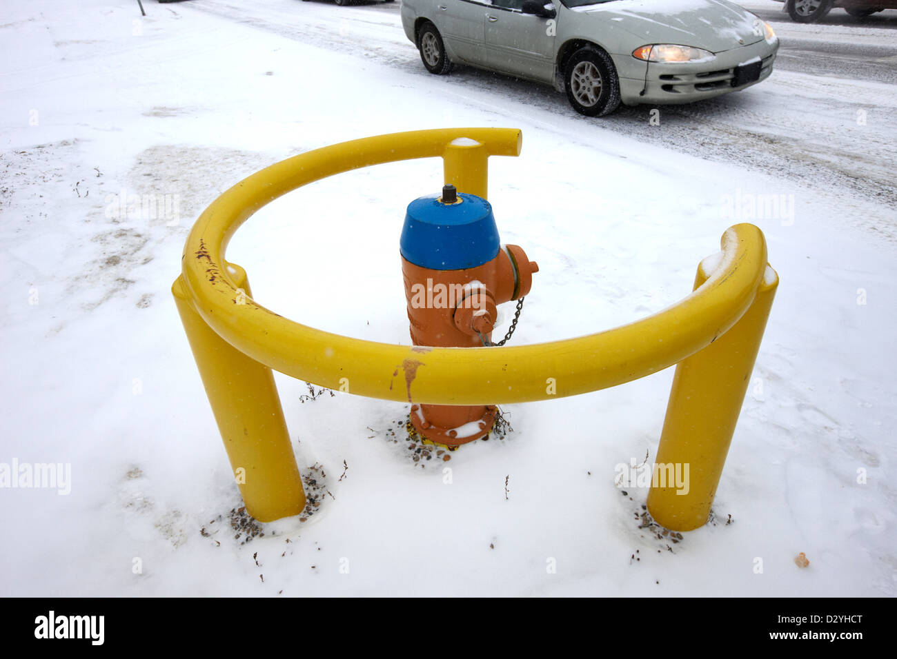 yellow fire hydrant with protective barrier in the snow by the side of ...