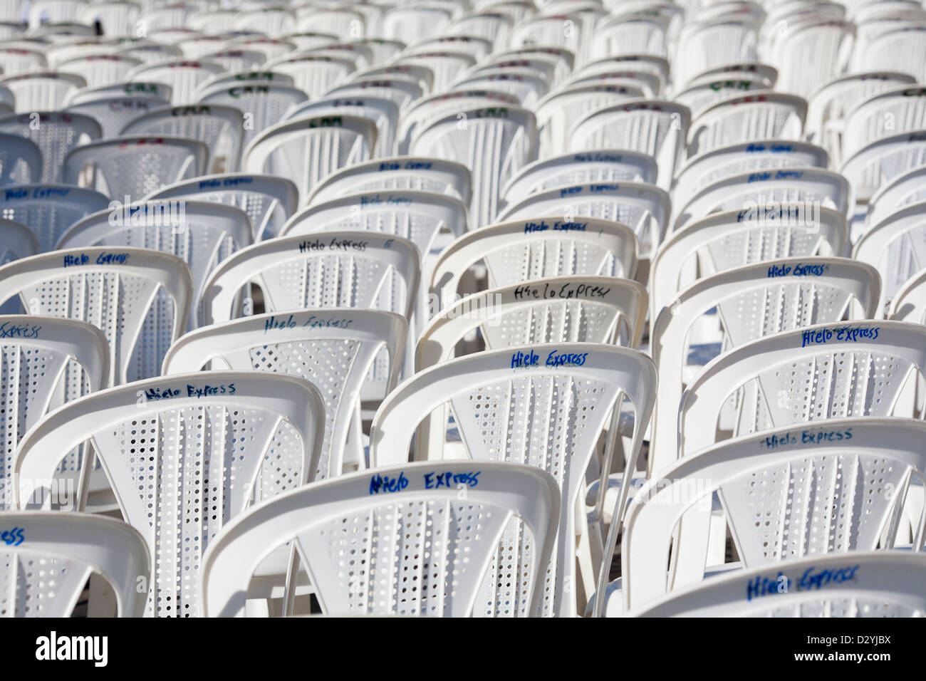 White plastic chairs lined up for a political rally in the town square ...