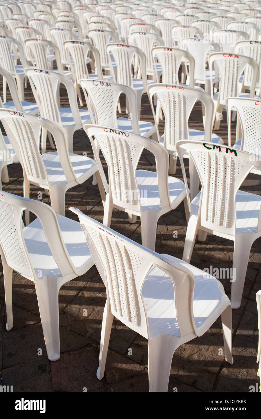 White plastic chairs lined up for a political rally in the town square ...