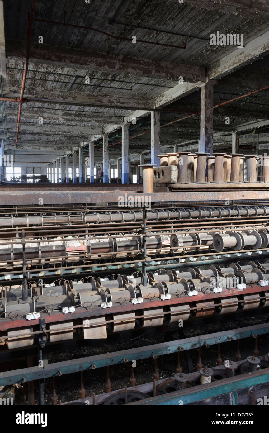 Textile mill machinery sits stopped in an empty closed and abandoned ...