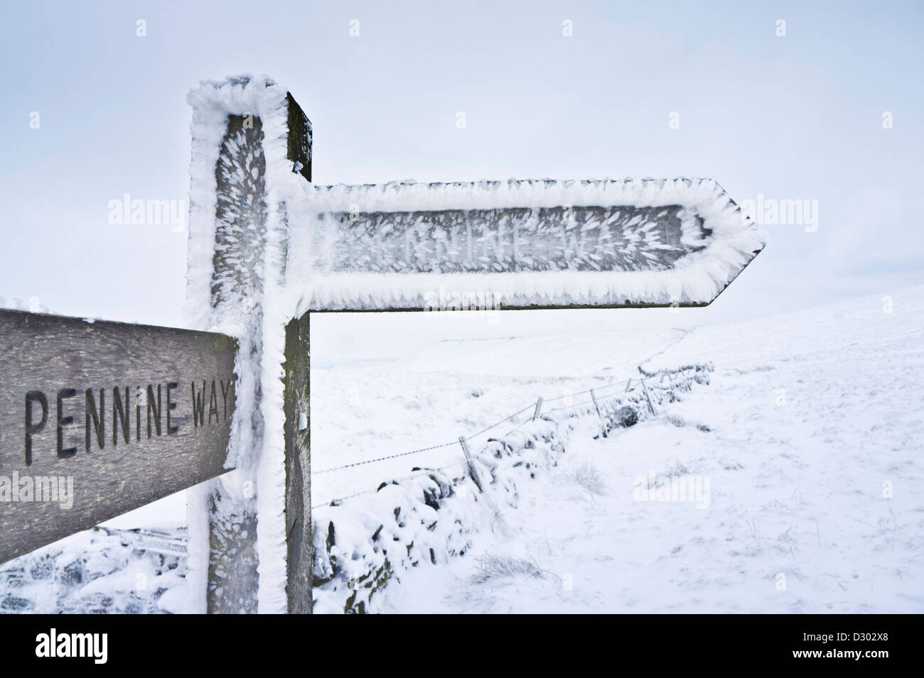 snow and ice covered signpost giving directions to the pennine way ...