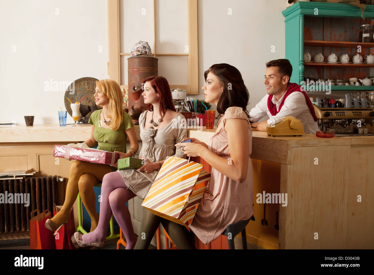 couple of friends gathered in a cafe sitting on chairs against the ...