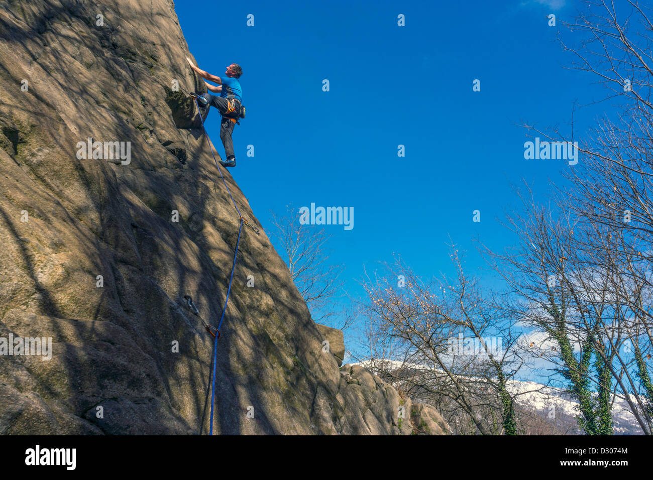 Rock climber in blue on slabby rock face Stock Photo - Alamy