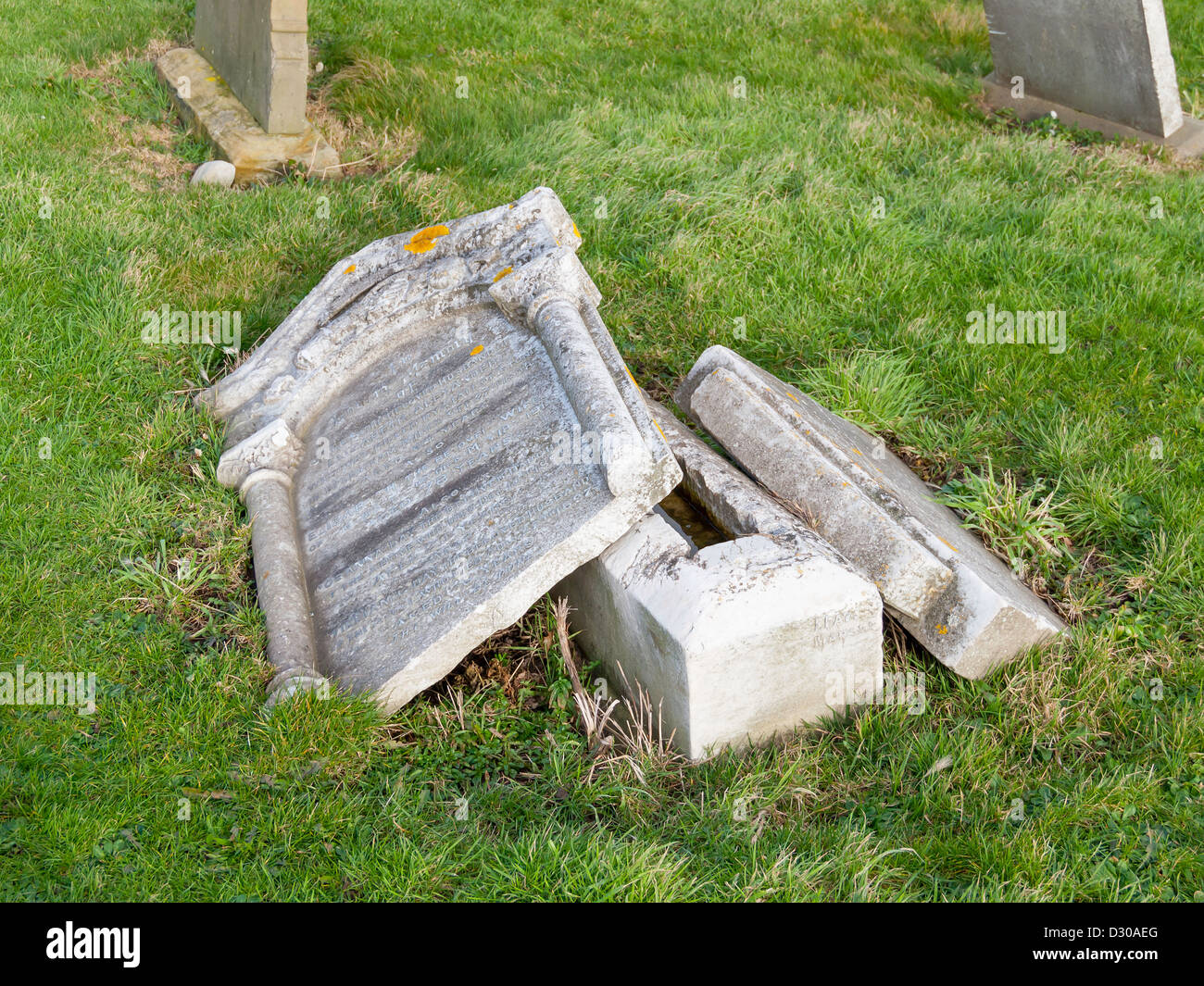 A toppled grave stone damaged by vandals Stock Photo - Alamy