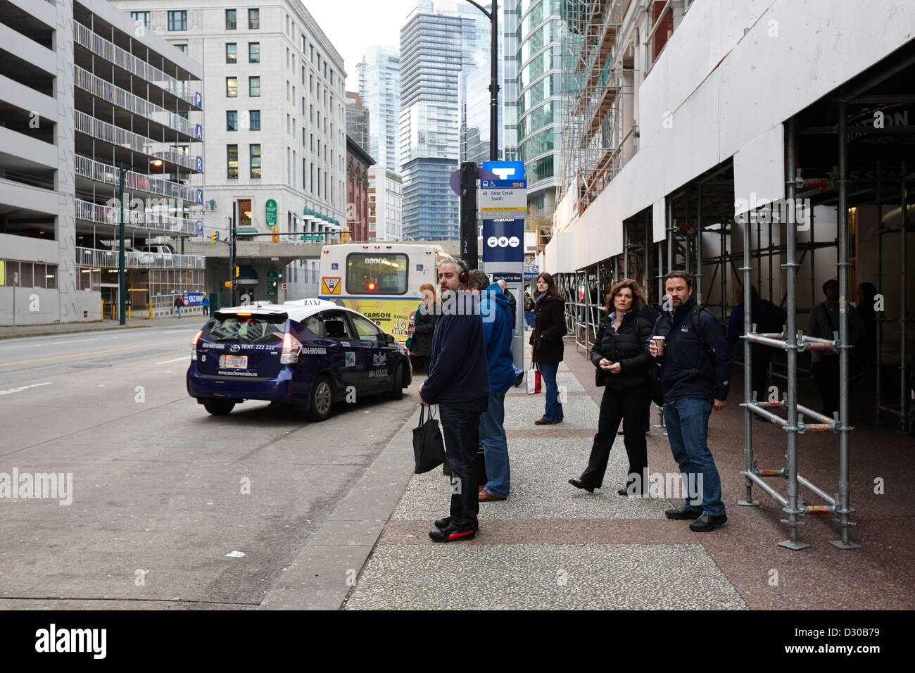 early morning commuters waiting for a bus at busstop outside waterfront ...