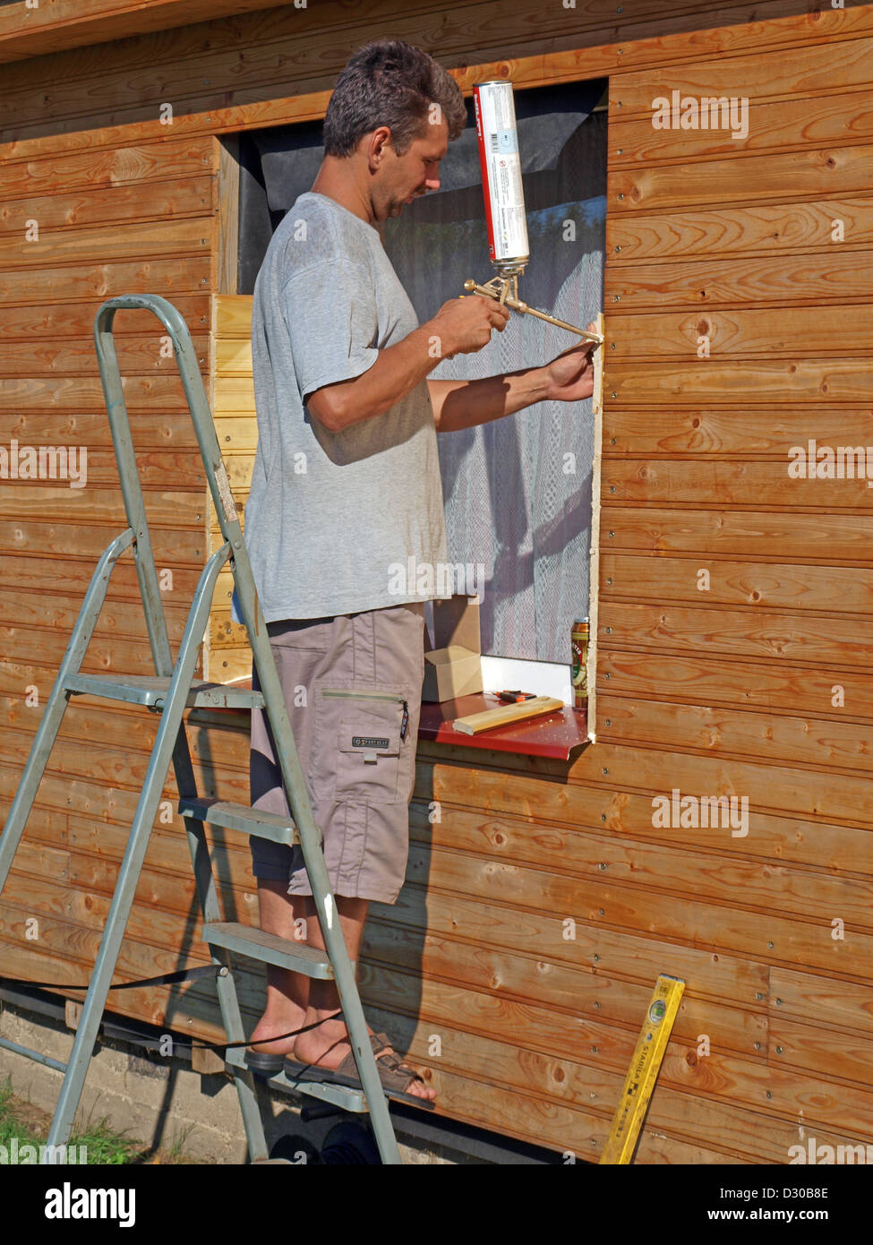 Adult man outdoor fill window frame with construction foam Stock Photo ...