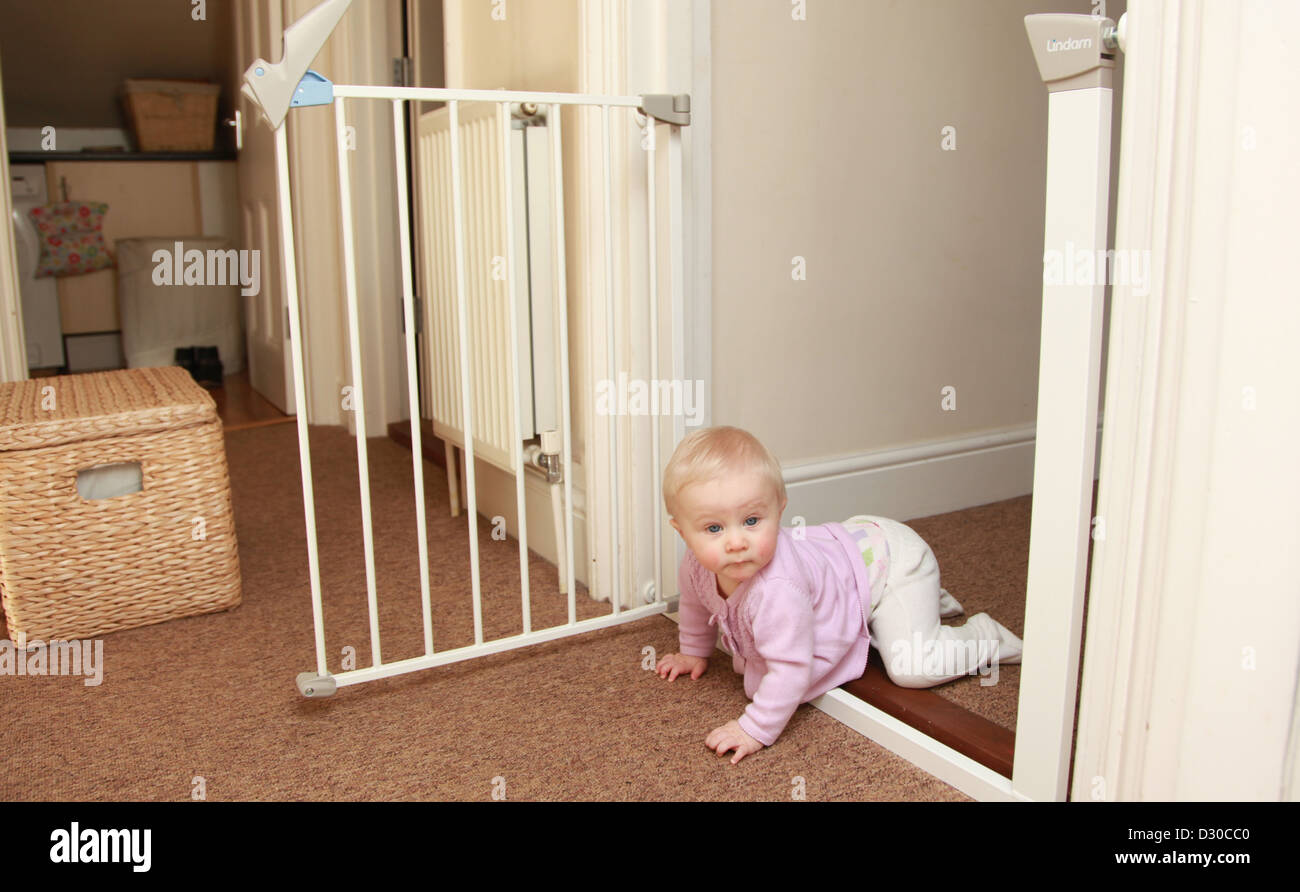 Baby crawling through open safety gate Stock Photo - Alamy