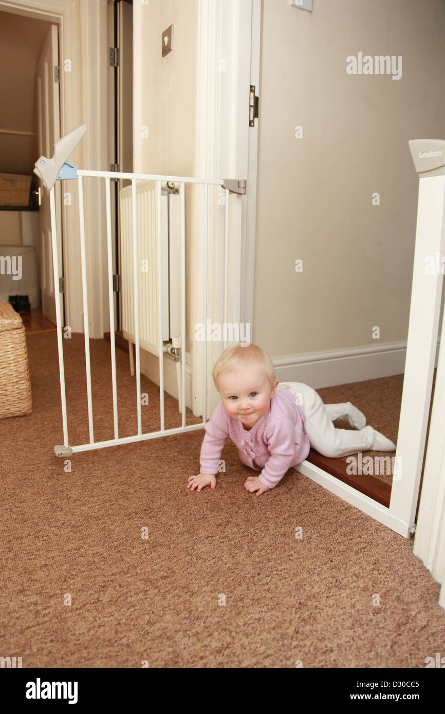 Baby crawling through open safety gate Stock Photo - Alamy