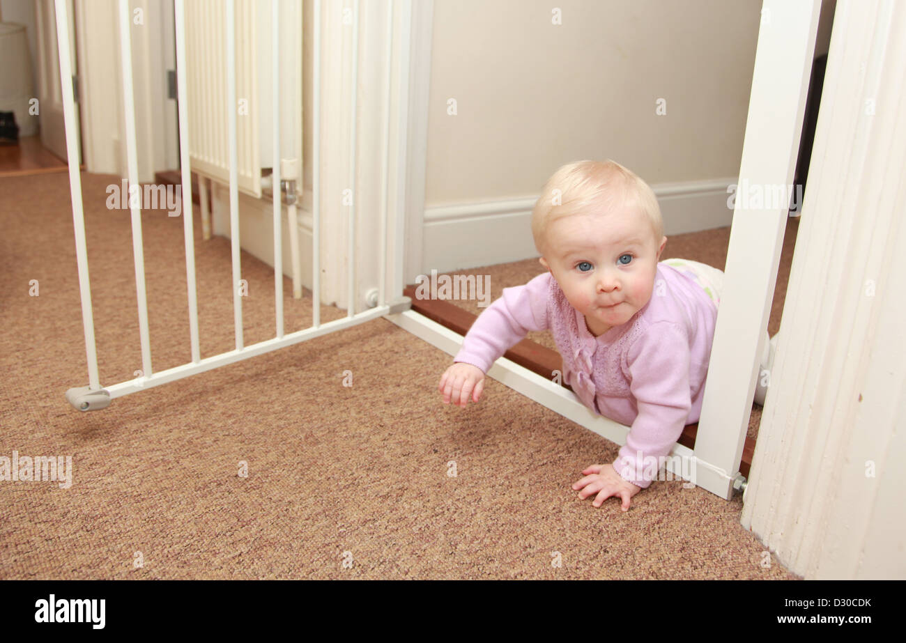 Baby crawling through open safety gate Stock Photo - Alamy