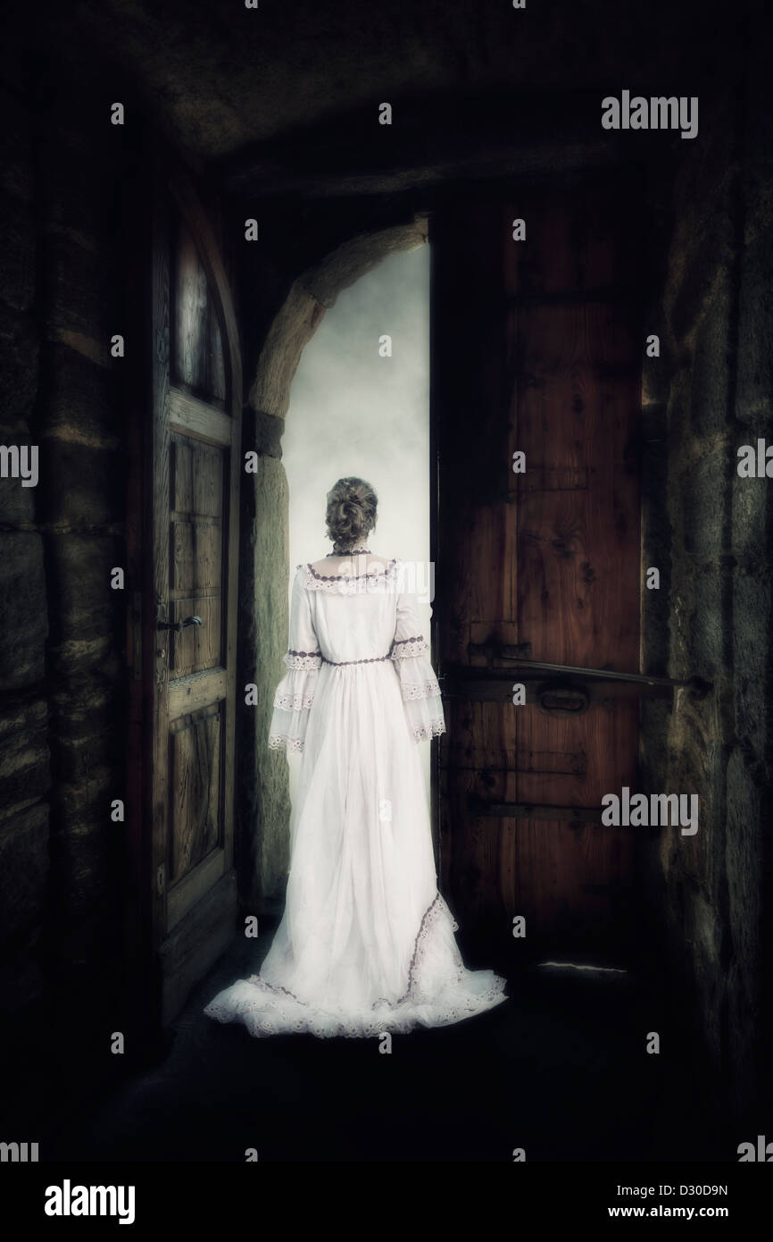 a woman in an elegant dress is standing in the gate of an old castle ...