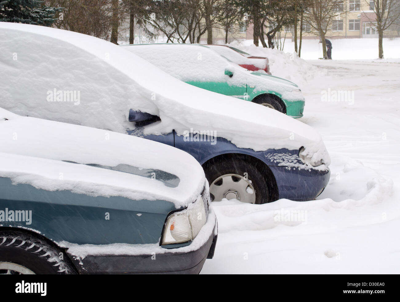 cars covered with falling blizzard snow standing in outdoor parking in ...