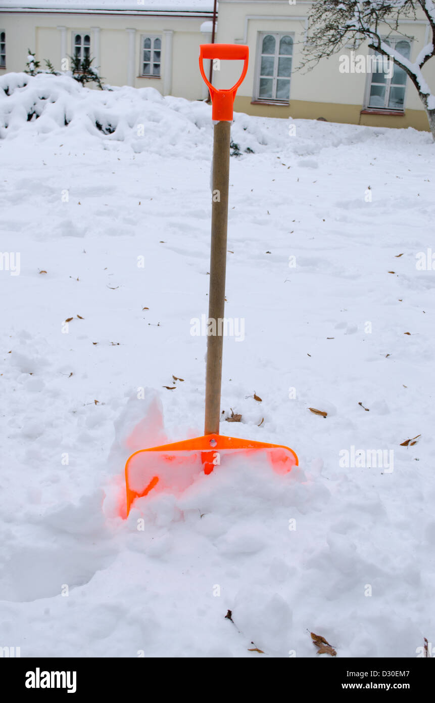orange plastic snow clean tool in winter snowdrift snow heap and house ...