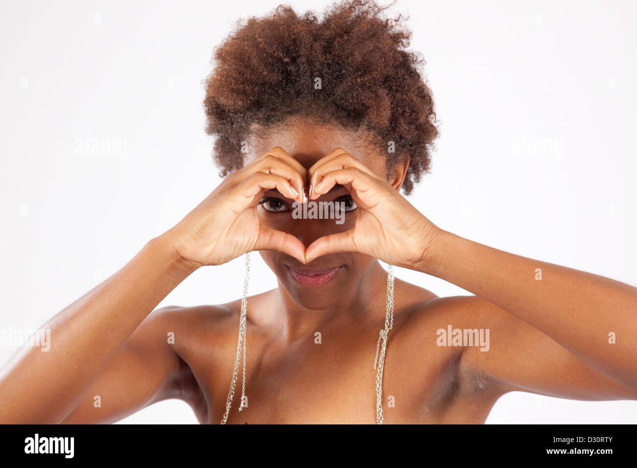 Woman making a heart shape with her hands and holding it over her eyes ...