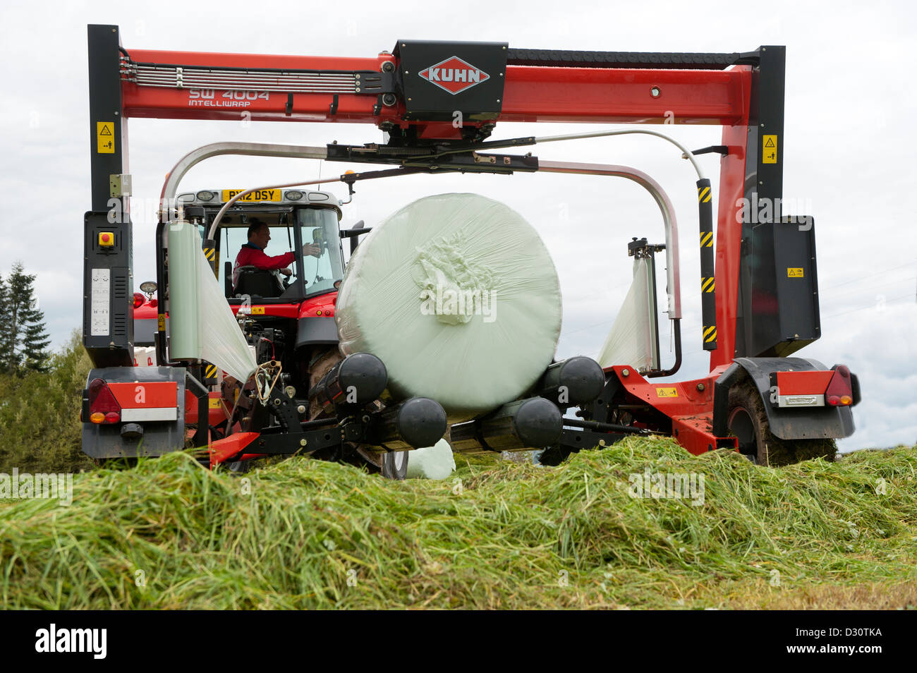 Wrapping round bale of silage with a Kuhn wrapper Stock Photo - Alamy