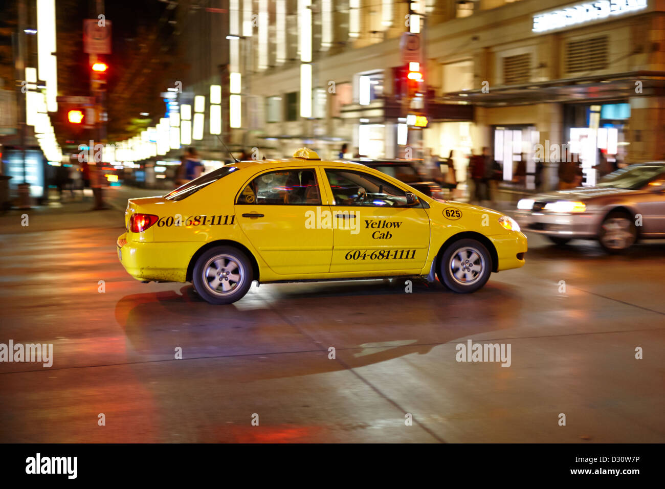 yellow cab taxi crossing junction downtown Vancouver city at night BC ...