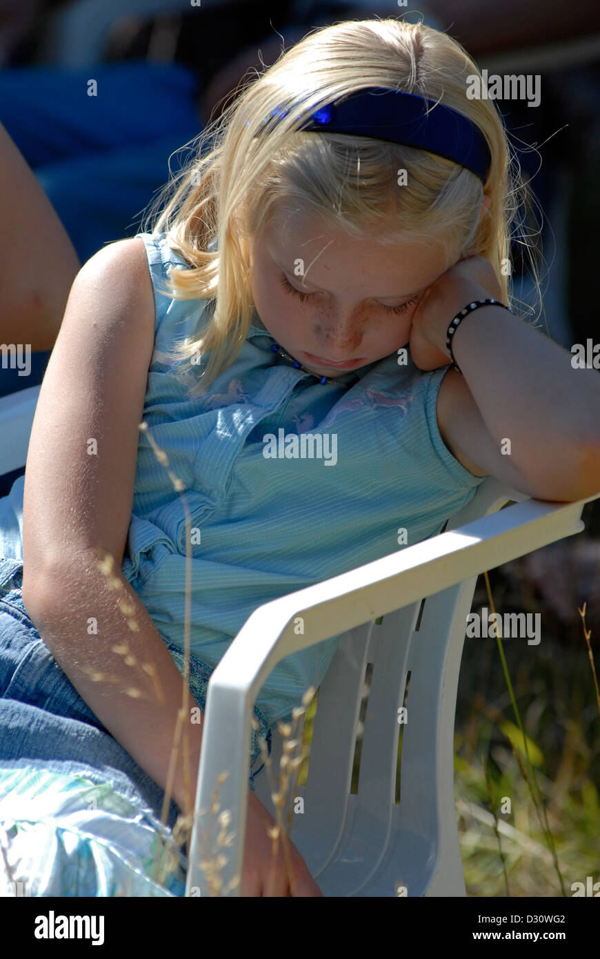 Girl napping in a chair at an outdoor wedding ceremony Stock Photo - Alamy