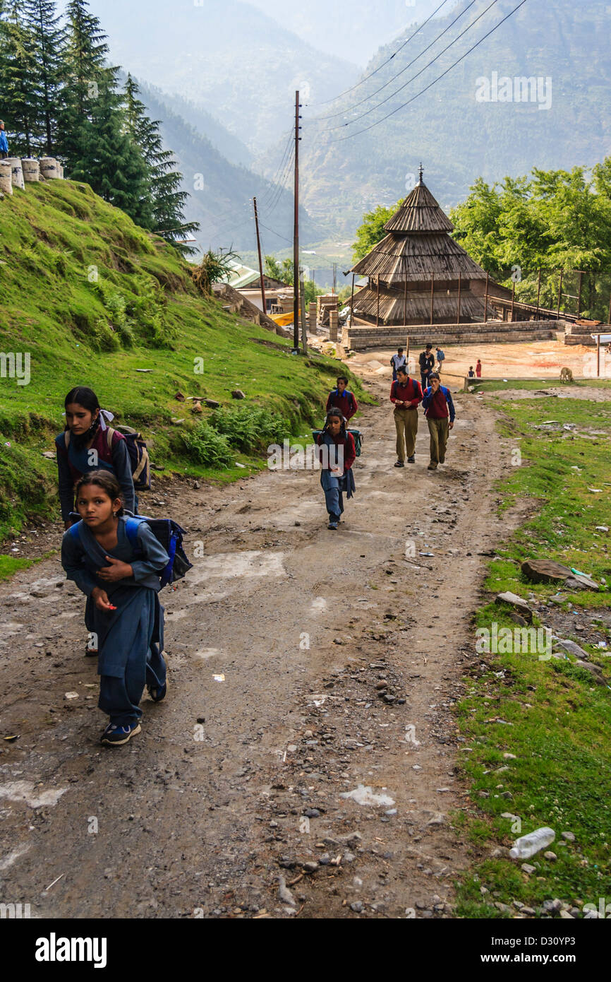 Indian school children going home on countryside path with temple and ...