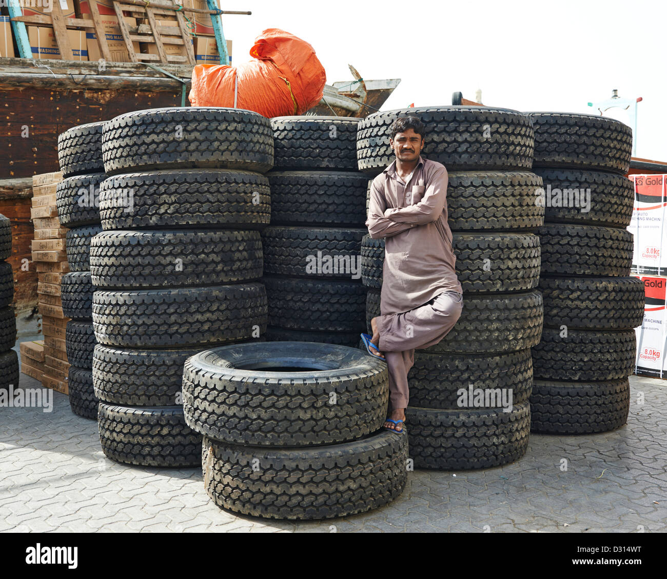 A man crosses his arm and raises his leg in front of a huge stack of ...