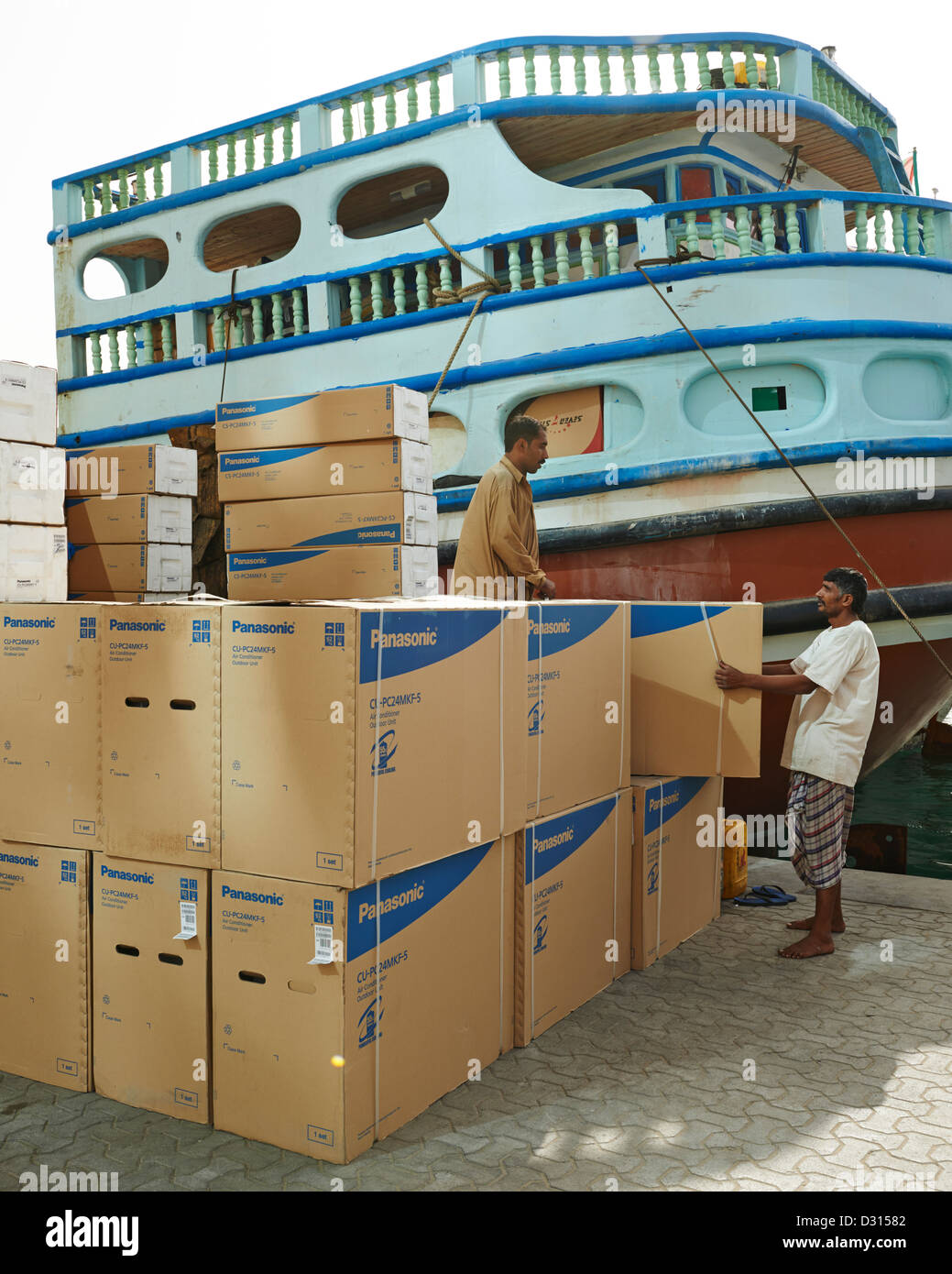 A labor worker carries heavy boxes of LCD Televisions on board a small ...