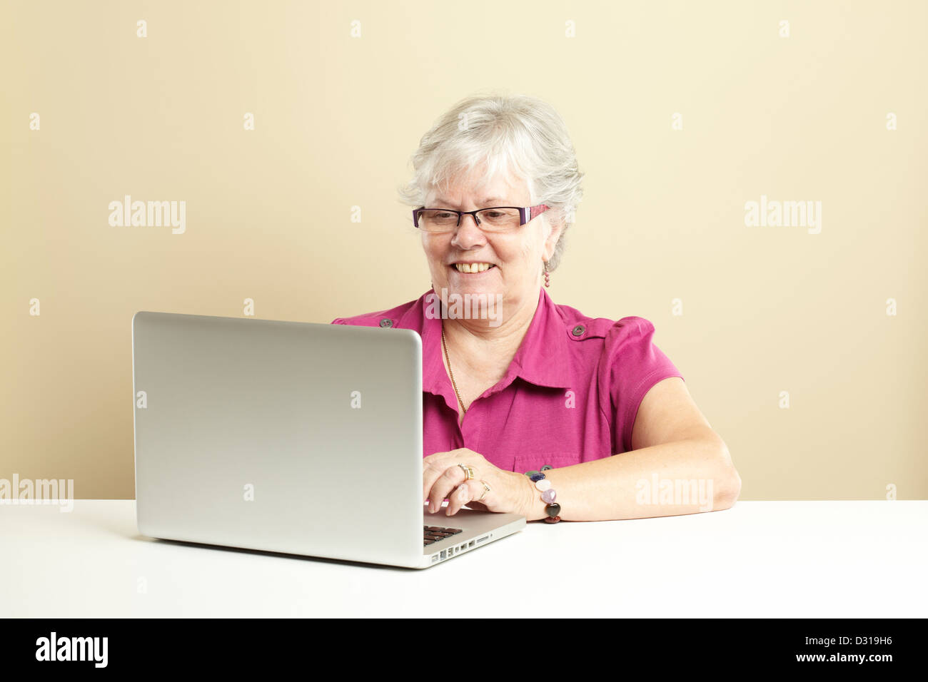 Senior woman using laptop whilst smiling Stock Photo - Alamy