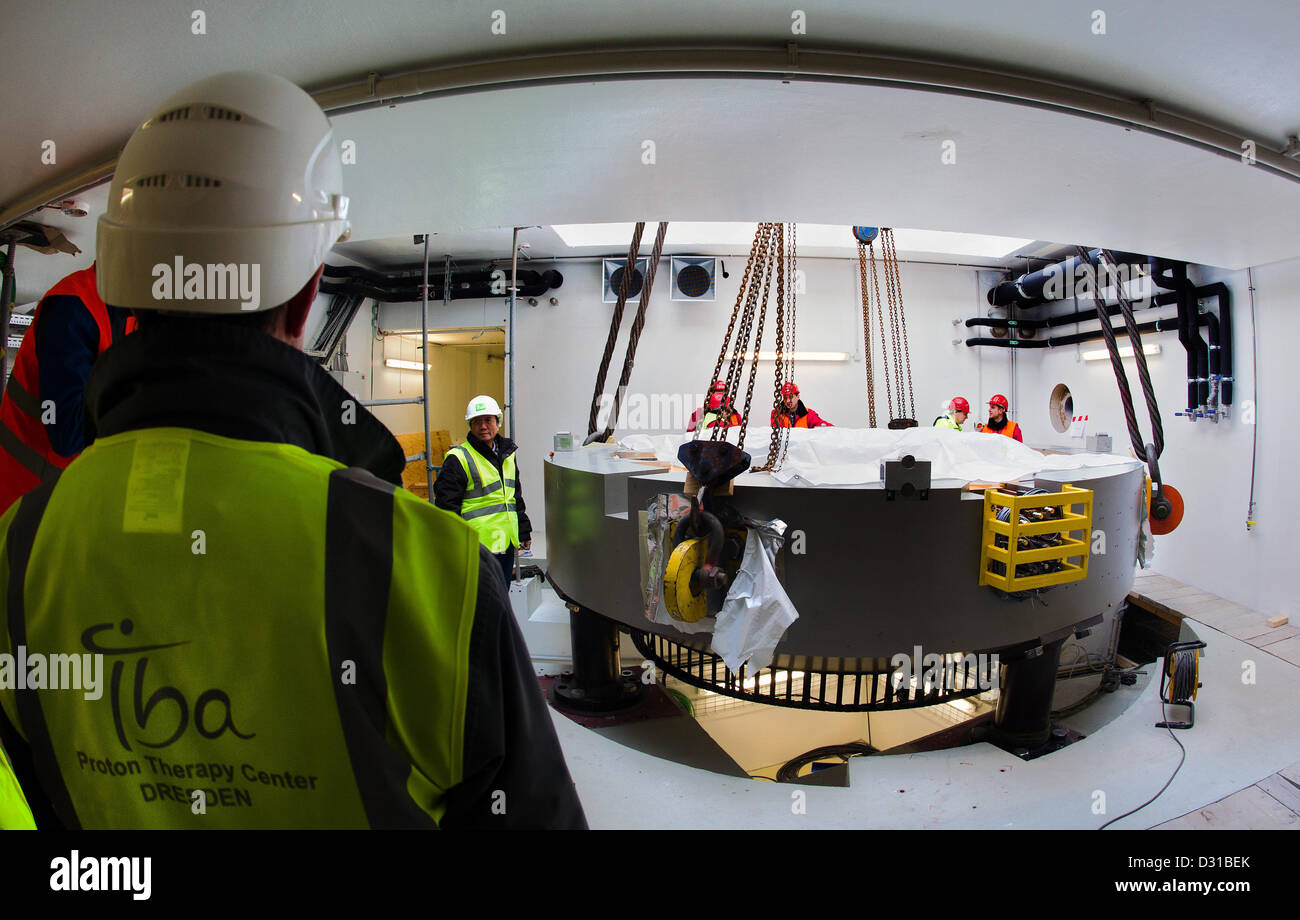 Workers install a component of a more than 220 tons heavy proton ...