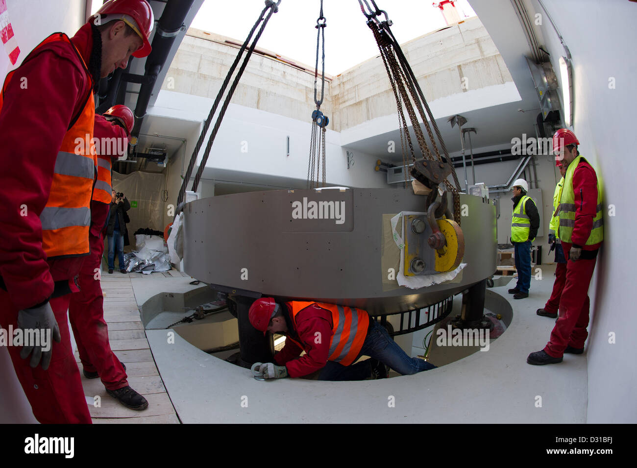 Workers install a component of a more than 220 tons heavy proton ...