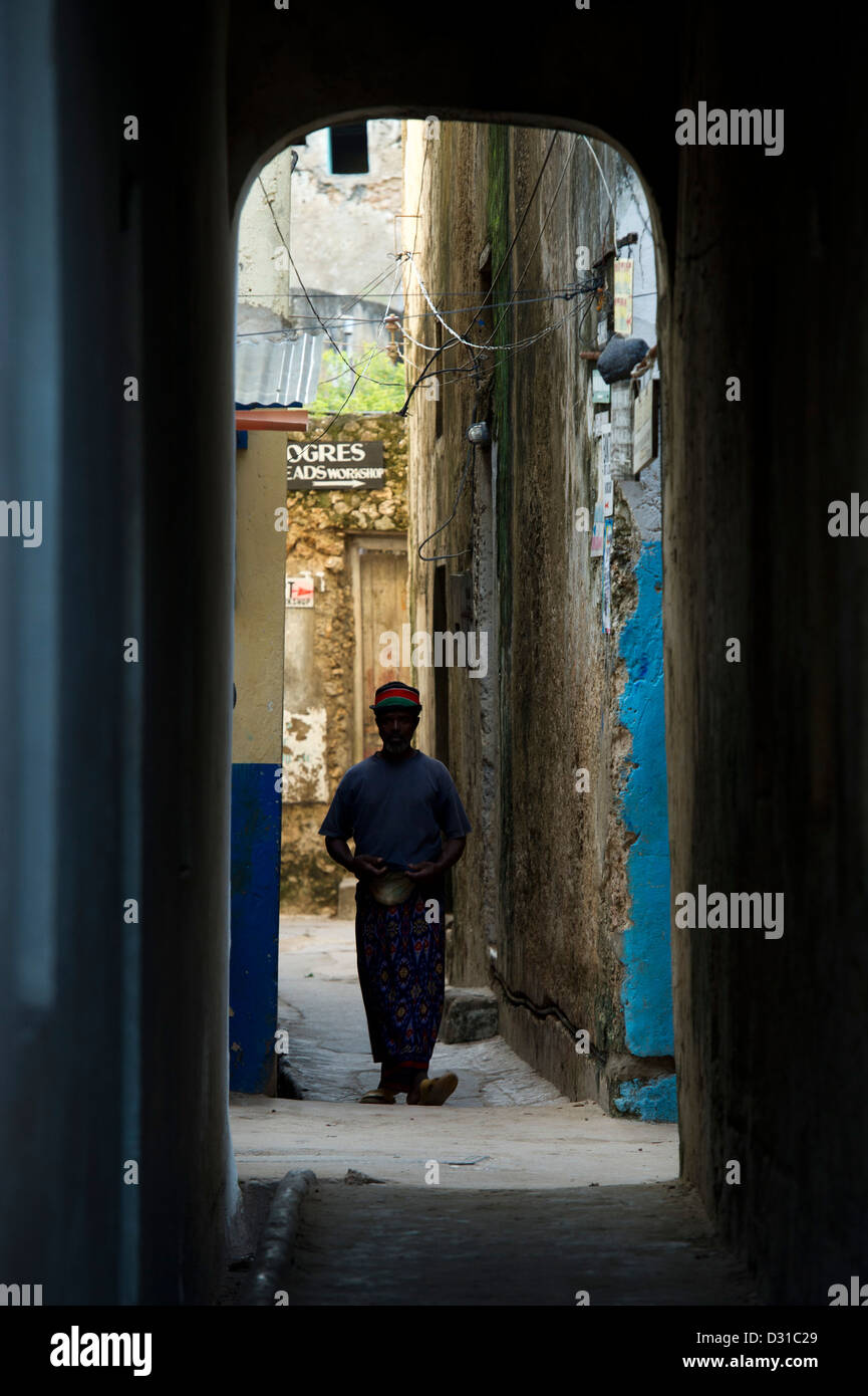 man walking through a narrow alley of Lamu town, Lamu Archipelago ...