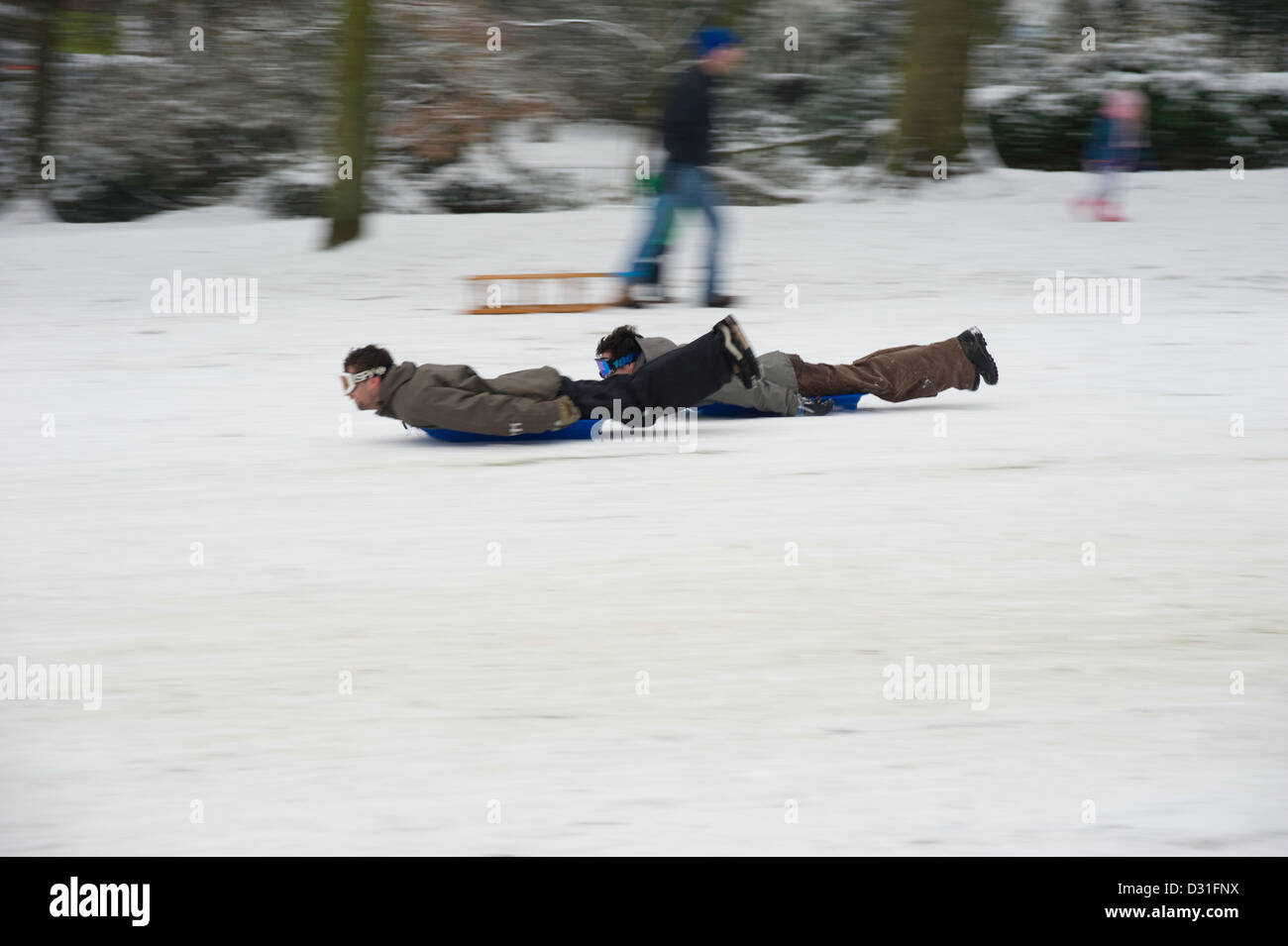Two men traveling at speed on sledges in the snow Stock Photo - Alamy