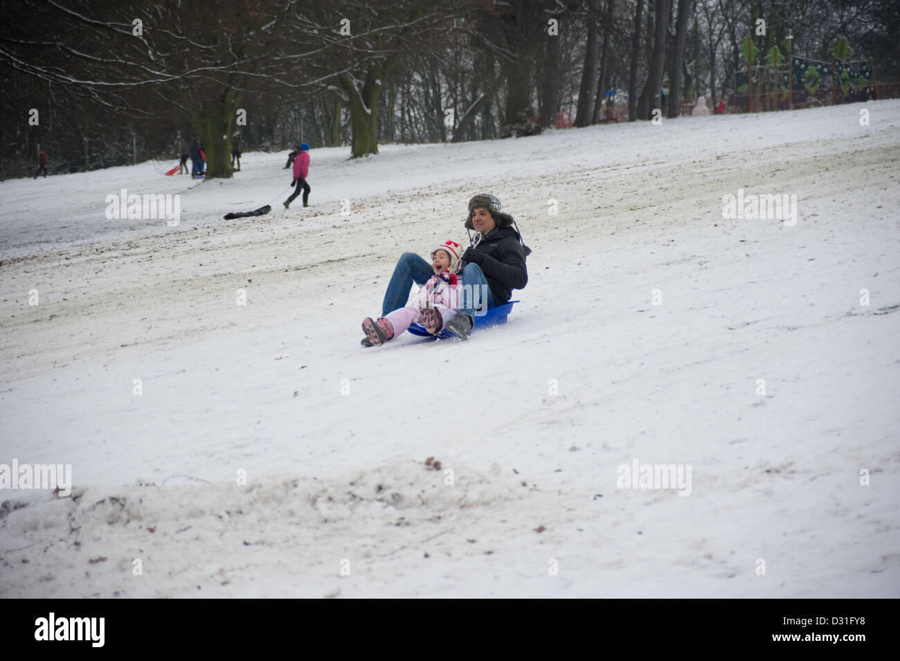 An Adult and small child on a sledge or toboggan going downhill in a ...