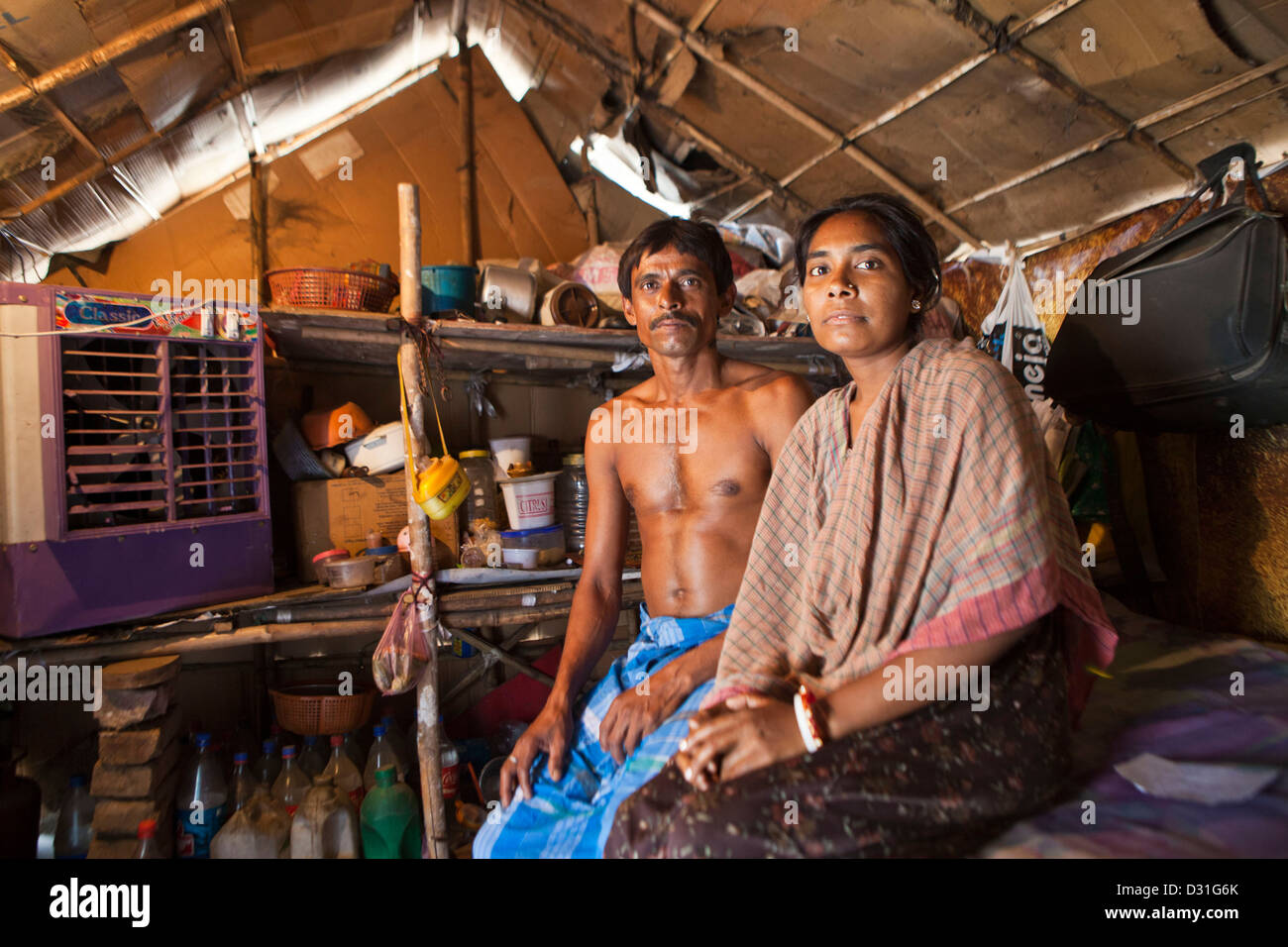 Poverty living in Tehkhand Slum, Delhi, India. A husband and wife sit ...
