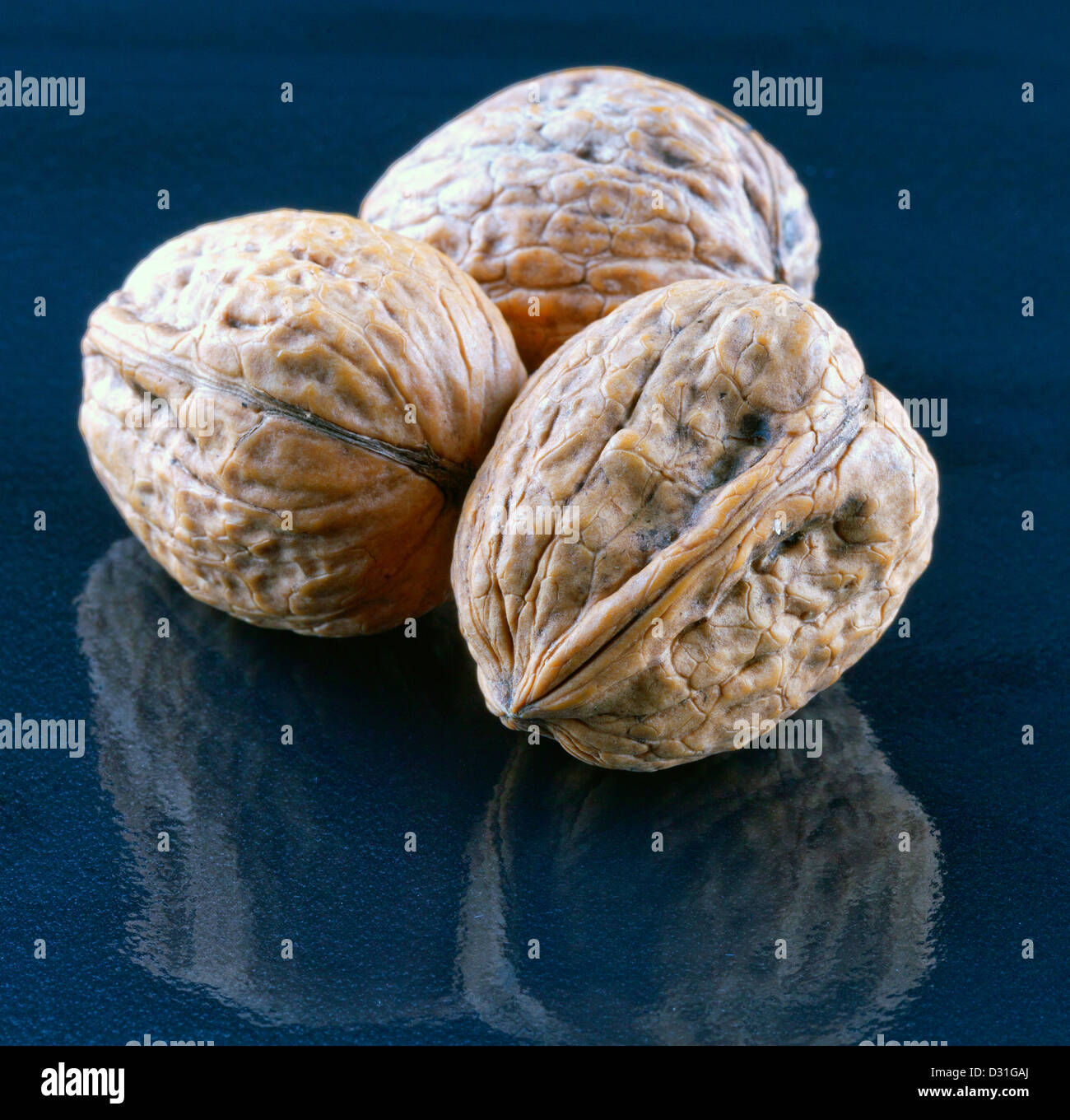 Three walnuts over a black reflecting surface Stock Photo - Alamy