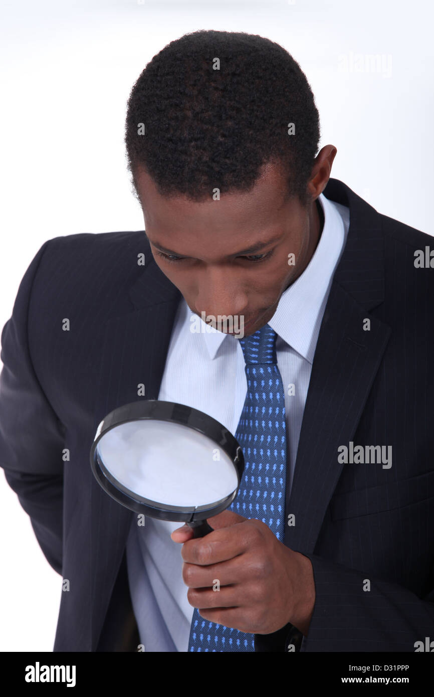 Curious man inspecting an object with a magnifying glass Stock Photo - Alamy