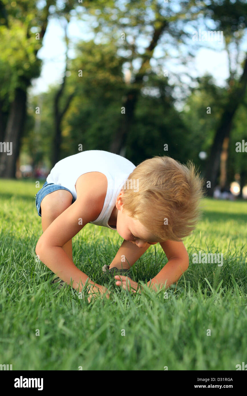 Little boy looking for lost thing in the grass Stock Photo - Alamy