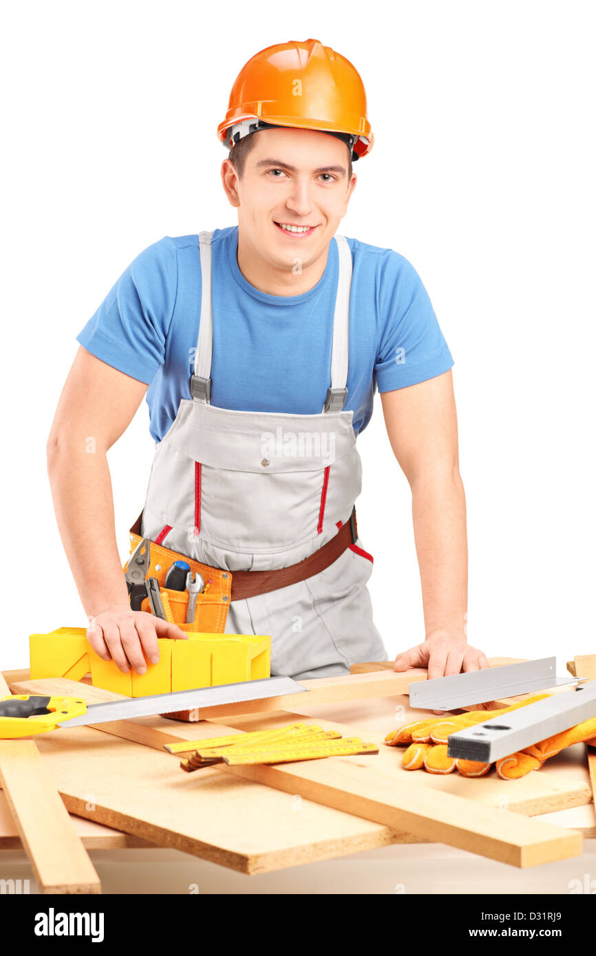 Manual worker standing next to a table with equipment and wooden pieces ...