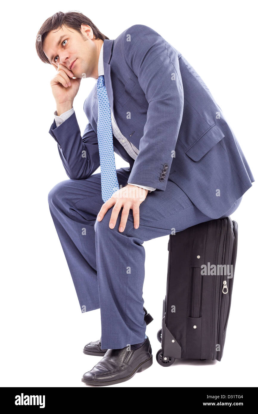 Portrait of a businessman sitting on his luggage isolated on white ...