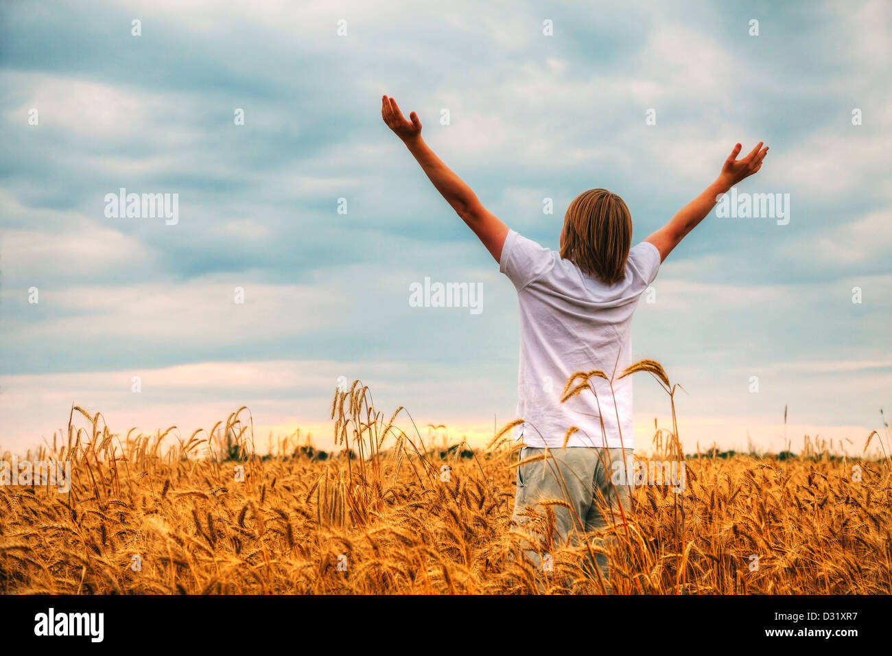 Young man staying with raised hands at sunset time Stock Photo - Alamy